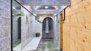 Uma sauna com parede de madeira, chão de mármore e um banco.