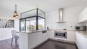Uma cozinha moderna com uma janela grande, forno embutido e micro-ondas.