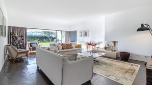 Uma sala de estar moderna com um sofá, poltronas, uma mesa de centro e uma lareira.
