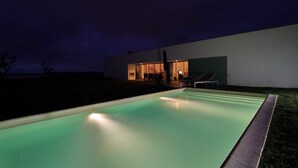 Um edifício moderno com piscina à noite.