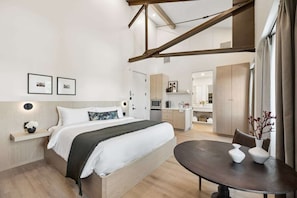 Quarto de hotel moderno com uma cama grande, uma mesa de jantar, cozinha e banheiro.