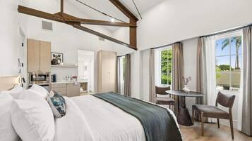 Quarto com cama, escrivaninha, cadeira e vista para o exterior.