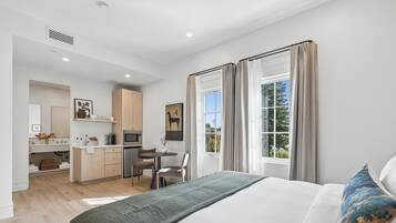 Quarto de hotel moderno com cama, escrivaninha e cozinha compacta.