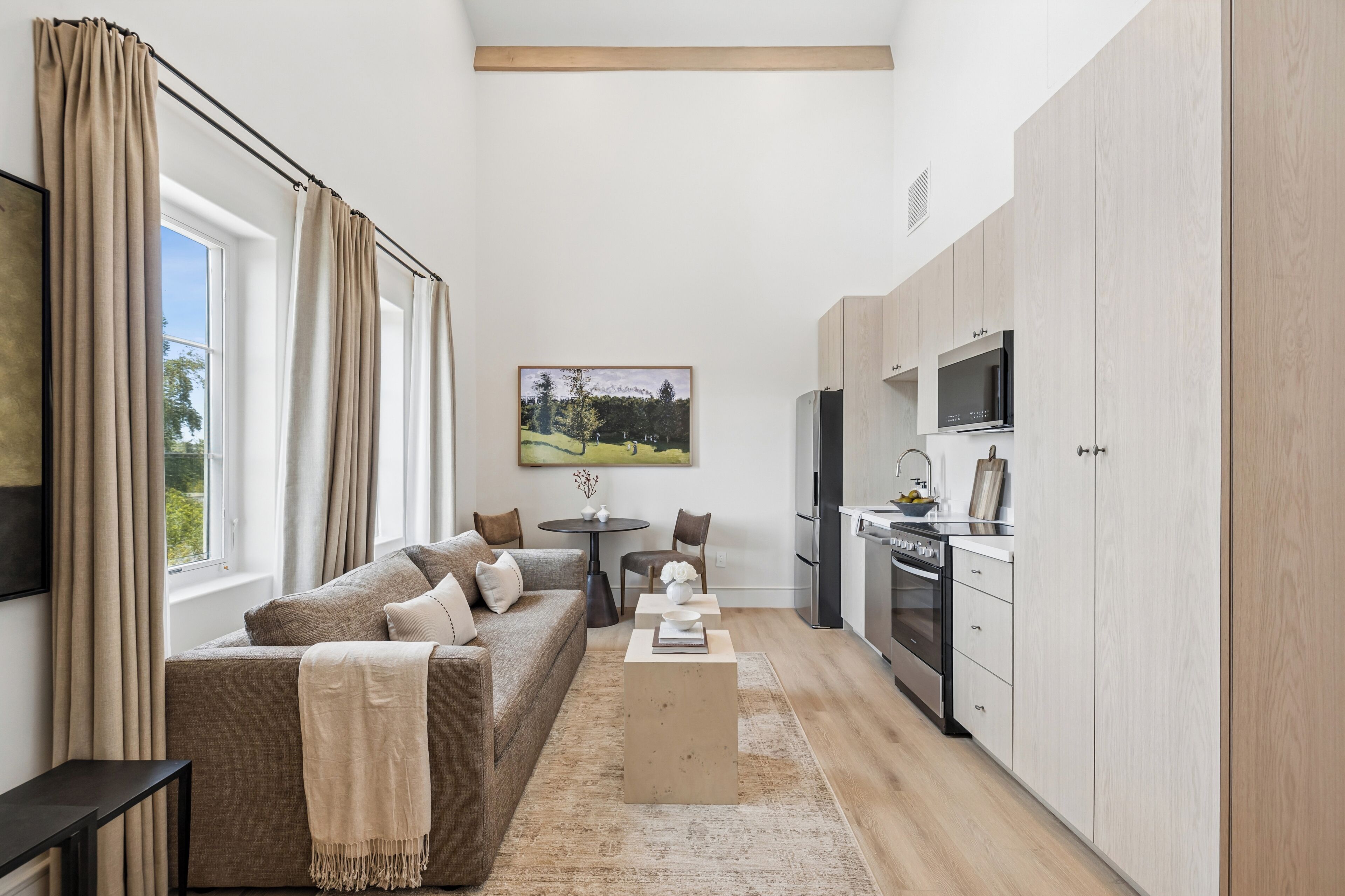 Uma sala de estar moderna com sofá, mesa de centro e área de cozinha com armários e eletrodomésticos.