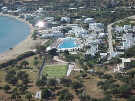 Uma área residencial à beira-mar, com edifícios brancos, piscina e quadra de tênis.