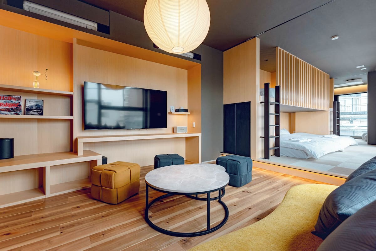 Quarto de hotel moderno com televisão de tela plana, uma mesa redonda, um sofá e uma cama.