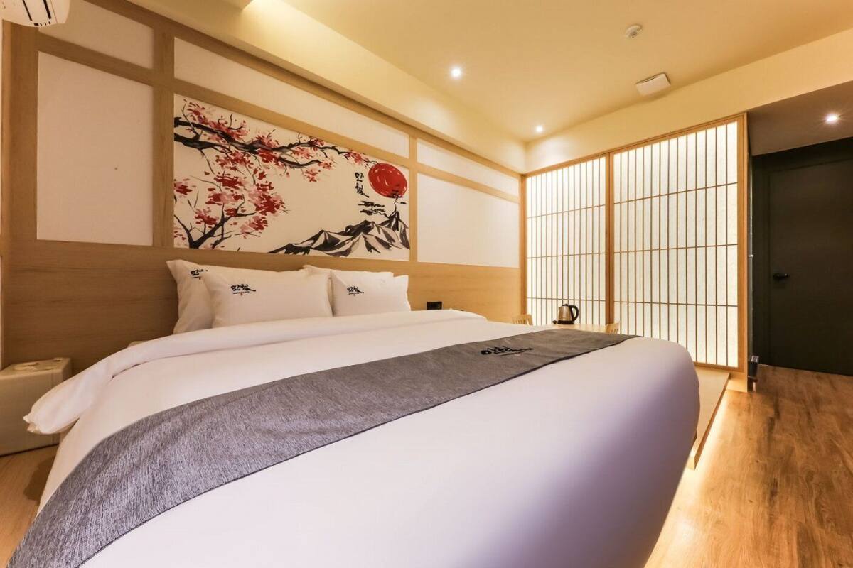 Quarto de hotel com uma cama grande, uma mesa de cabeceira, uma obra de arte na parede e uma porta de correr.
