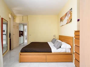 Quarto com cama, cômoda de madeira e um quadro na parede.