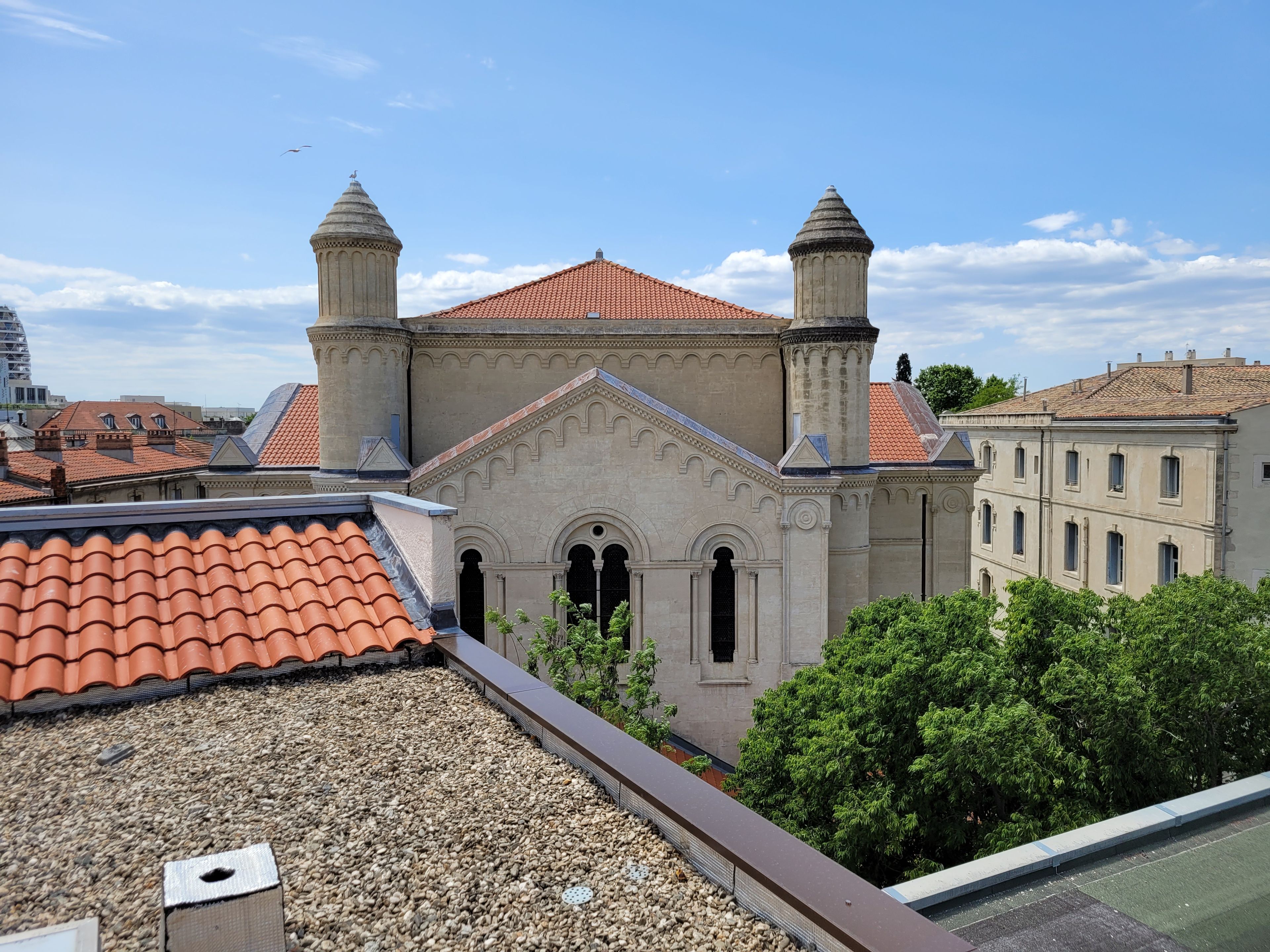 Um edifício com telhado de telhas vermelhas, duas torres e janelas em arco.