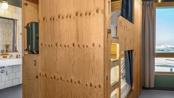 Quarto de madeira com cozinha compacta, uma cama e vista para a cidade.