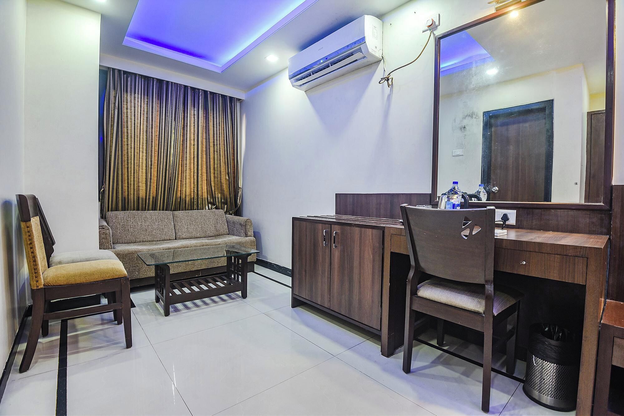 Quarto moderno com sofá, escrivaninha de madeira, cadeira e aparelho de ar condicionado.