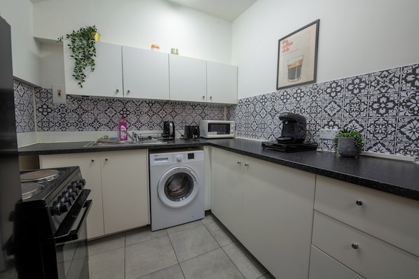 Uma cozinha compacta equipada com máquina de lavar, micro-ondas e cafeteira.