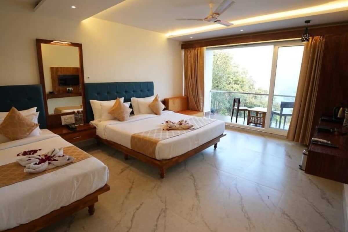 Quarto de hotel com duas camas, varanda, televisão e secretária.