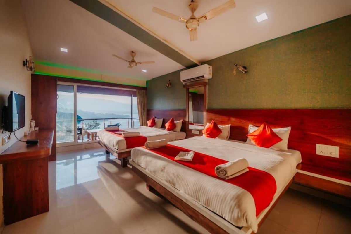 Quarto de hotel com duas camas, uma escrivaninha, televisão e ar condicionado.