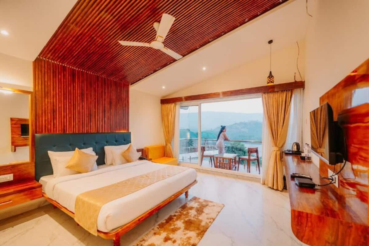 Quarto com uma cama grande, um ventilador de teto, uma TV e uma varanda com vista.