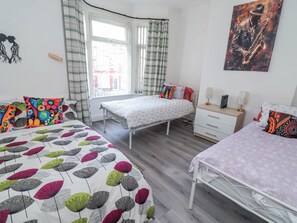 Quarto com duas camas, uma cômoda, uma janela com cortinas e um quadro na parede.