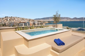 Piscina no terraço com vista para a cidade e montanhas.