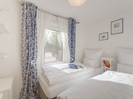 Quarto com duas camas, mesa de cabeceira com abajur e janela com cortinas.