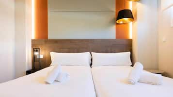 Uma cama de casal com lençóis brancos, cabeceira de madeira e duas luminárias de cabeceira.