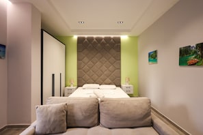 Quarto moderno com uma cama grande, duas mesas de cabeceira e uma cabeceira com padrão de losangos.