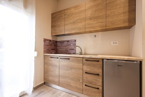 Cozinha com armários de madeira, painel de backsplash de pedra e lava-louças embutida.