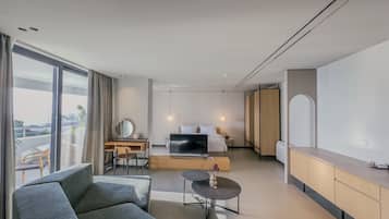 Uma sala de estar moderna com sofá, mesa de jantar, TV e área de cozinha com armários.