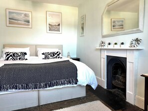 Quarto com cama, lareira e quadros nas paredes.