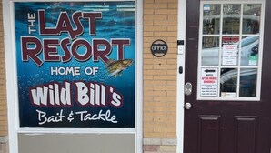 Um edifício com uma placa anunciando 'The Last Resort Home of Wild Bill's Bait & Tackle'.