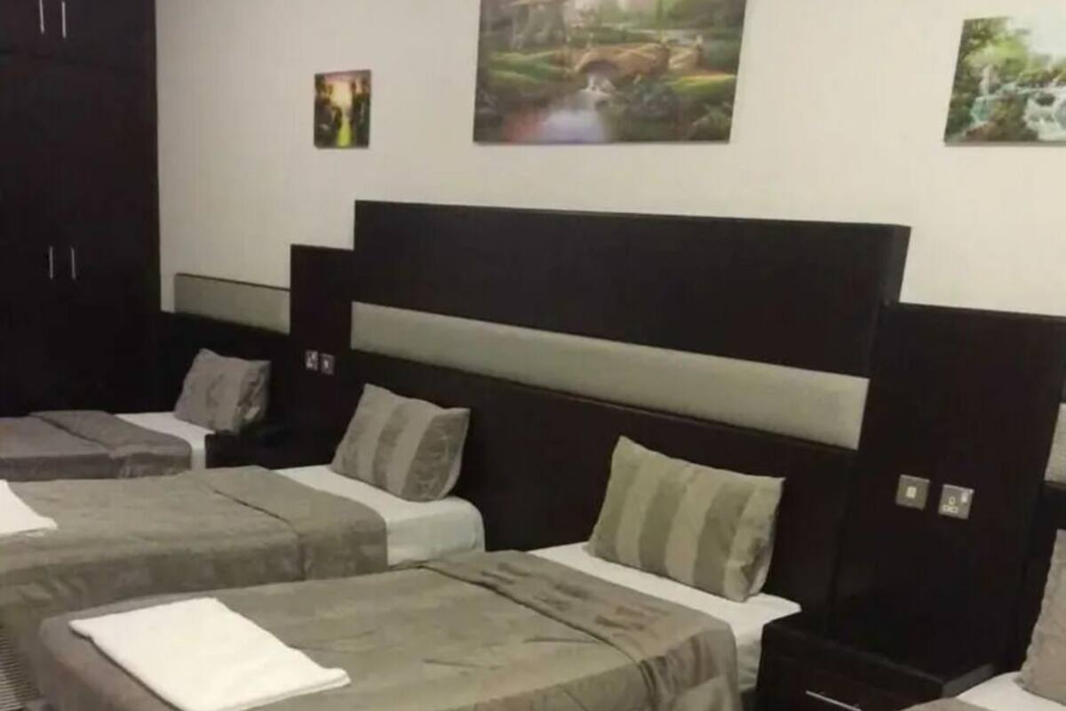 Quarto de hotel com duas camas, uma cabeceira escura e um quadro na parede.