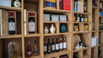 Uma estante de madeira com vários livros, garrafas de vinho e objetos decorativos.