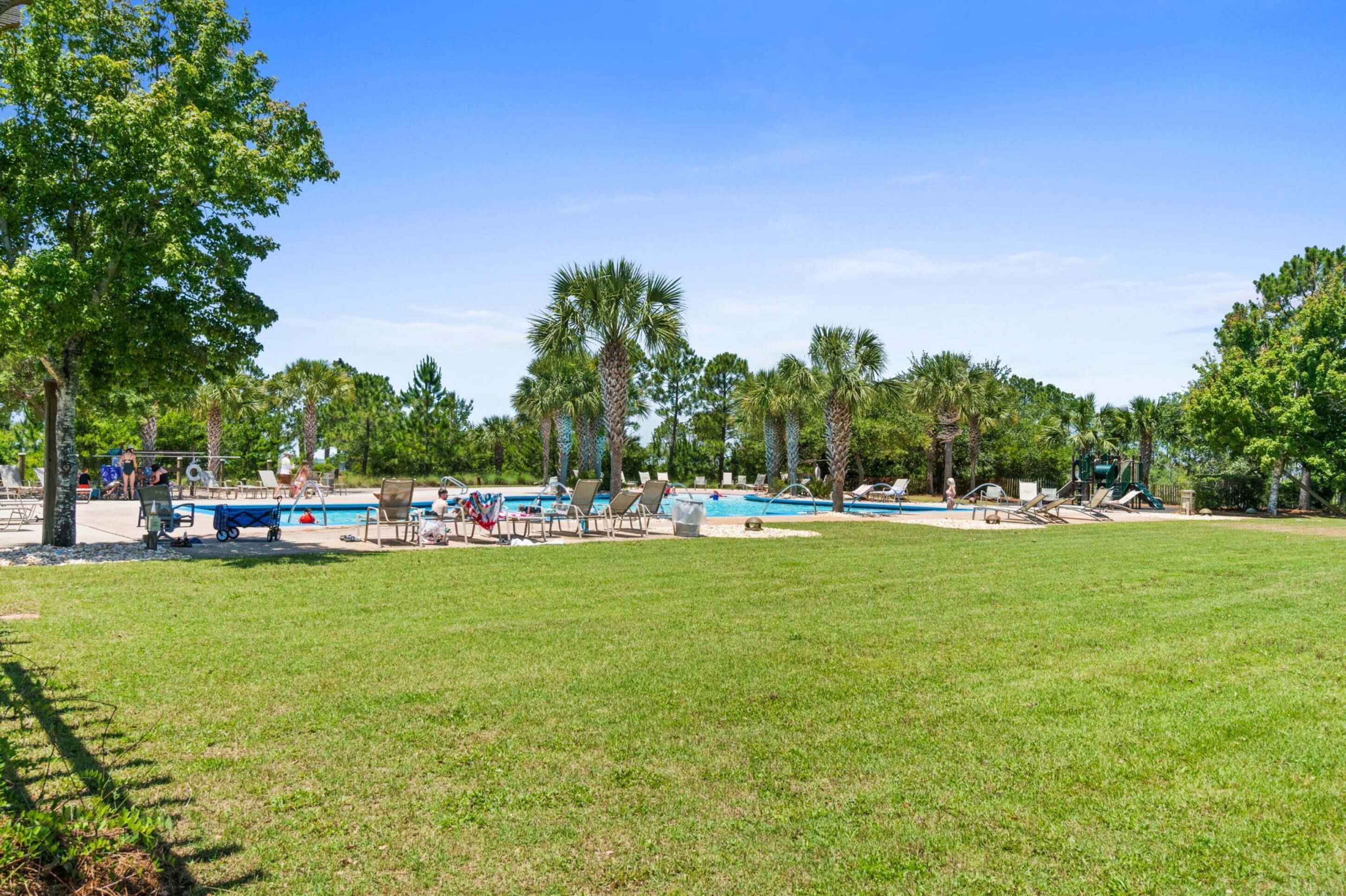 Uma área de piscina com várias piscinas, espreguiçadeiras e palmeiras.