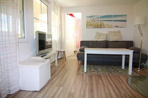 Sala de estar com televisão, sofá, mesa de centro e abajur.