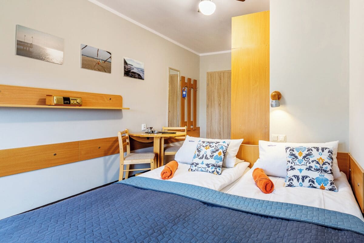 Quarto de hotel com uma cama, uma escrivaninha e uma cadeira.