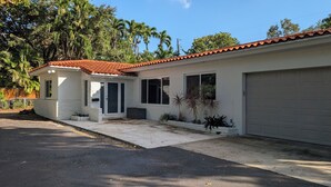 Uma casa térrea com telhado de telhas vermelhas, garagem e pequeno alpendre.