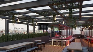 Um bar no terraço com mesas, bancos e um balcão, além de vista para a cidade.