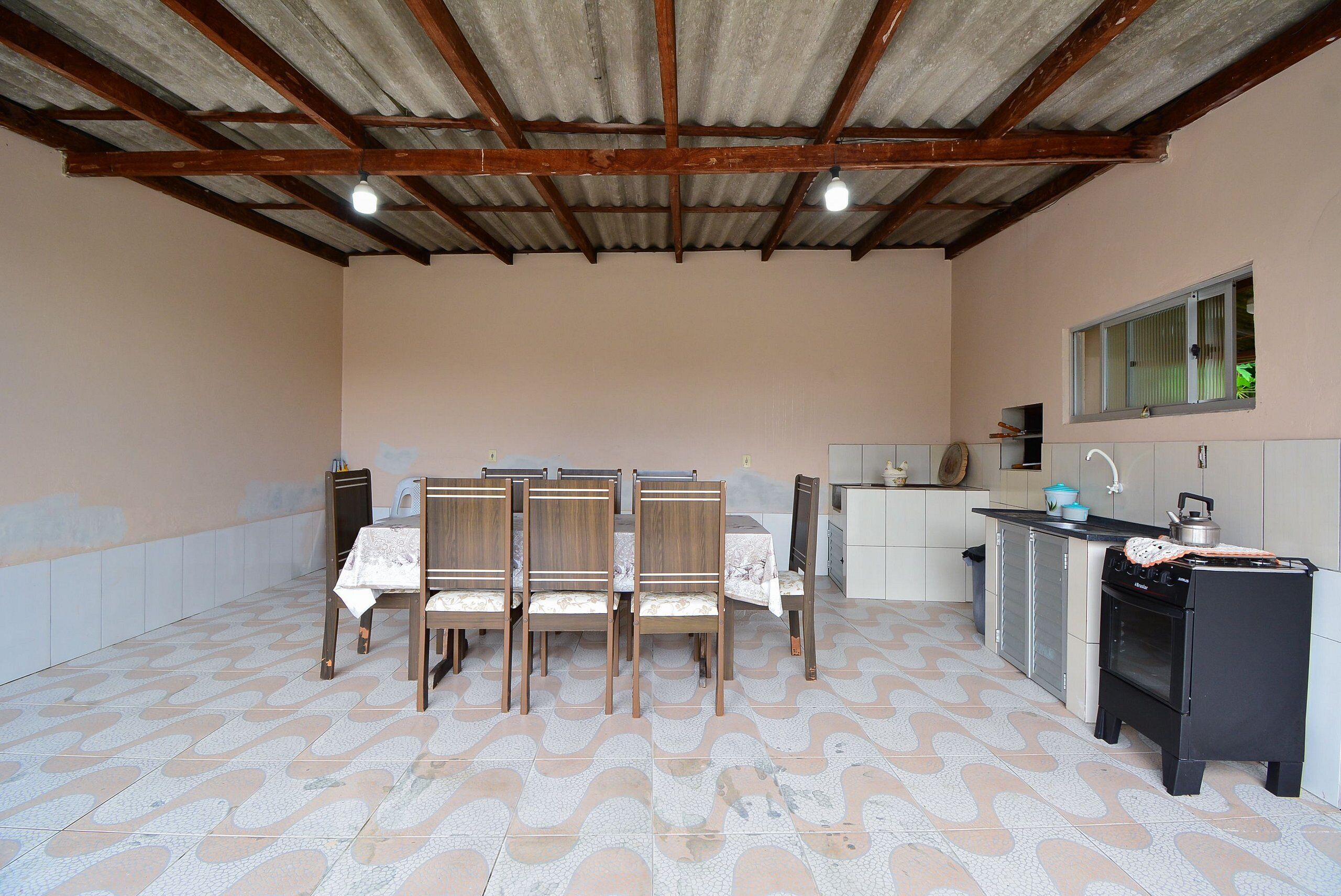 Uma cozinha com piso em azulejos, uma mesa de jantar com cadeiras, uma pia e um fogão.
