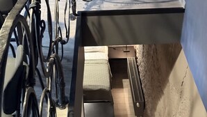 Uma escadaria com padrão de piso xadrez, corrimãos de metal e um banco.