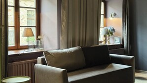 Quarto com sofá, luminária, janela com cortinas e radiador.