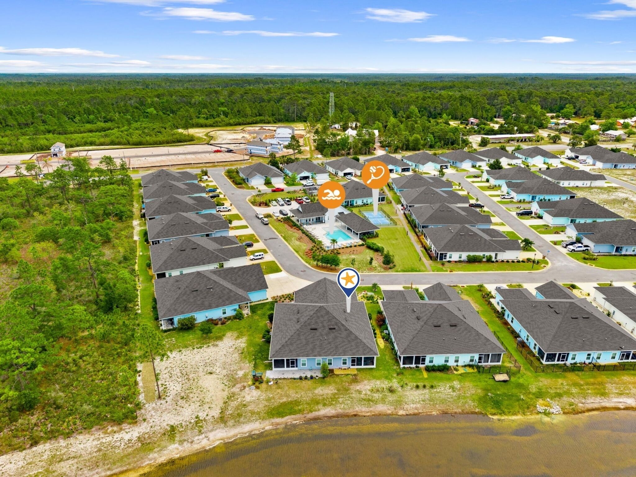 Vista aérea de um bairro residencial com várias casas de dois andares, uma piscina e uma rua.