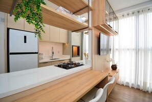 Cozinha moderna com geladeira, fogão e bancadas brancas.