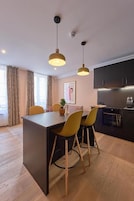 Uma cozinha moderna com iluminação pendente, uma área de jantar com ilha central e vista para a cidade.