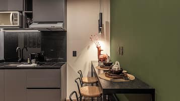 Uma cozinha moderna com área de refeições, micro-ondas, cafeteira e um vaso com flores.