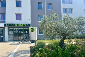 Um hotel tipo bed and breakfast com fachada moderna, uma bicicleta estacionada na frente e uma árvore em primeiro plano.
