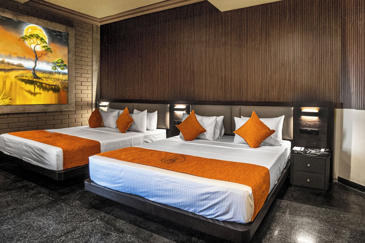 Quarto de hotel com duas camas, uma mesa de cabeceira e um quadro pendurado na parede.