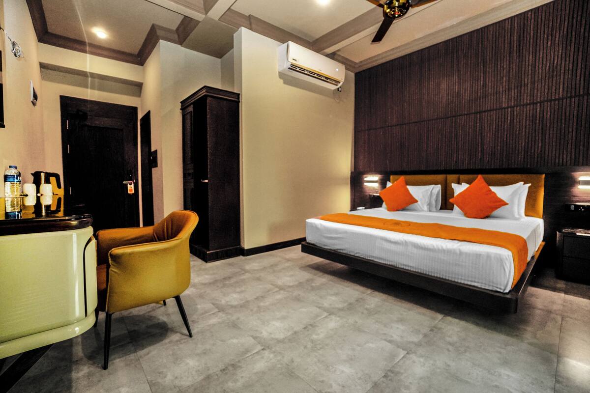 Quarto de hotel com cama, cadeira, escrivaninha e ar condicionado.