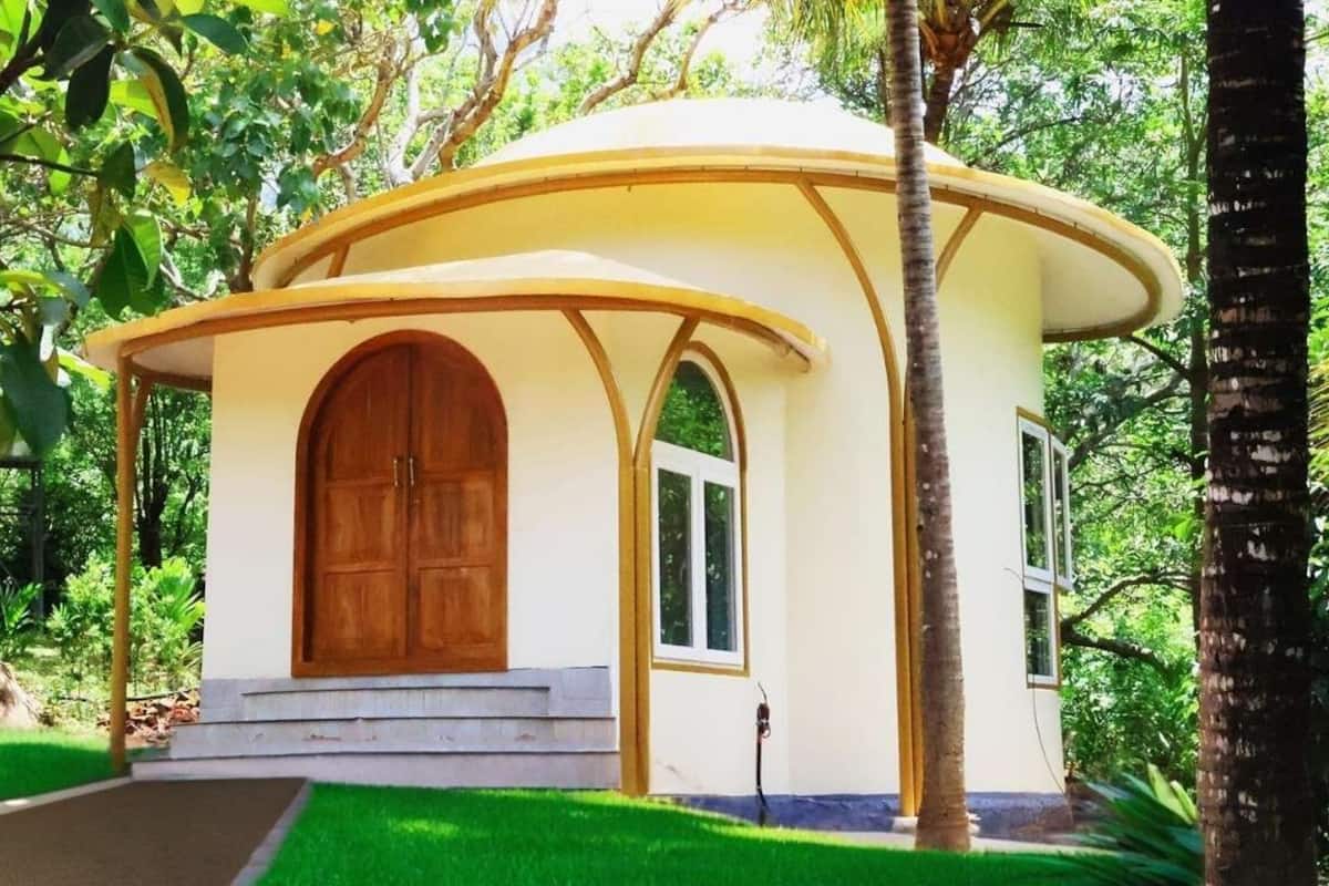 Um pequeno edifício térreo com telhado curvo, porta de madeira e uma janela.
