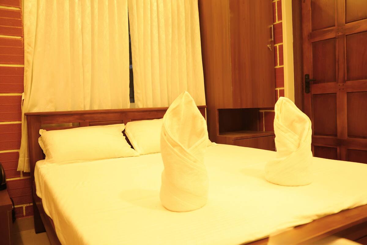 Quarto de hotel com cama, cabeceira de madeira, mesa de cabeceira e porta de madeira.