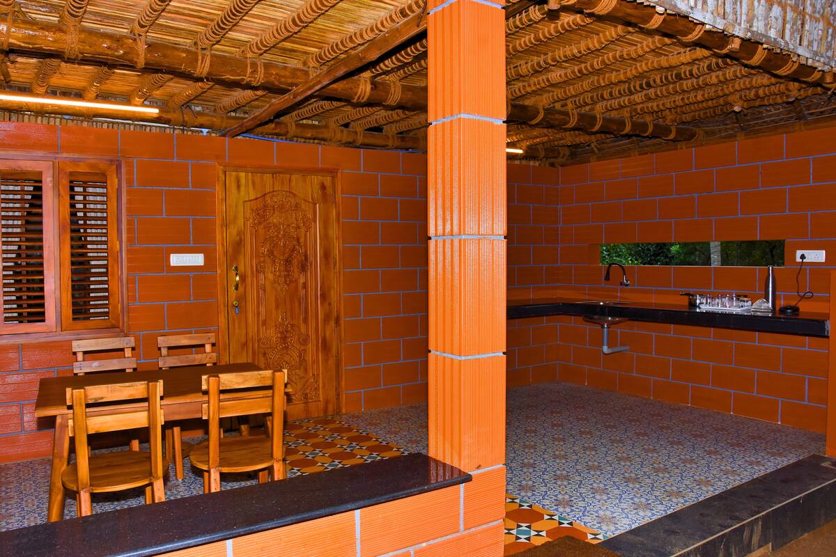 Uma cozinha com mesa e cadeiras de madeira, pia e chão de azulejos.