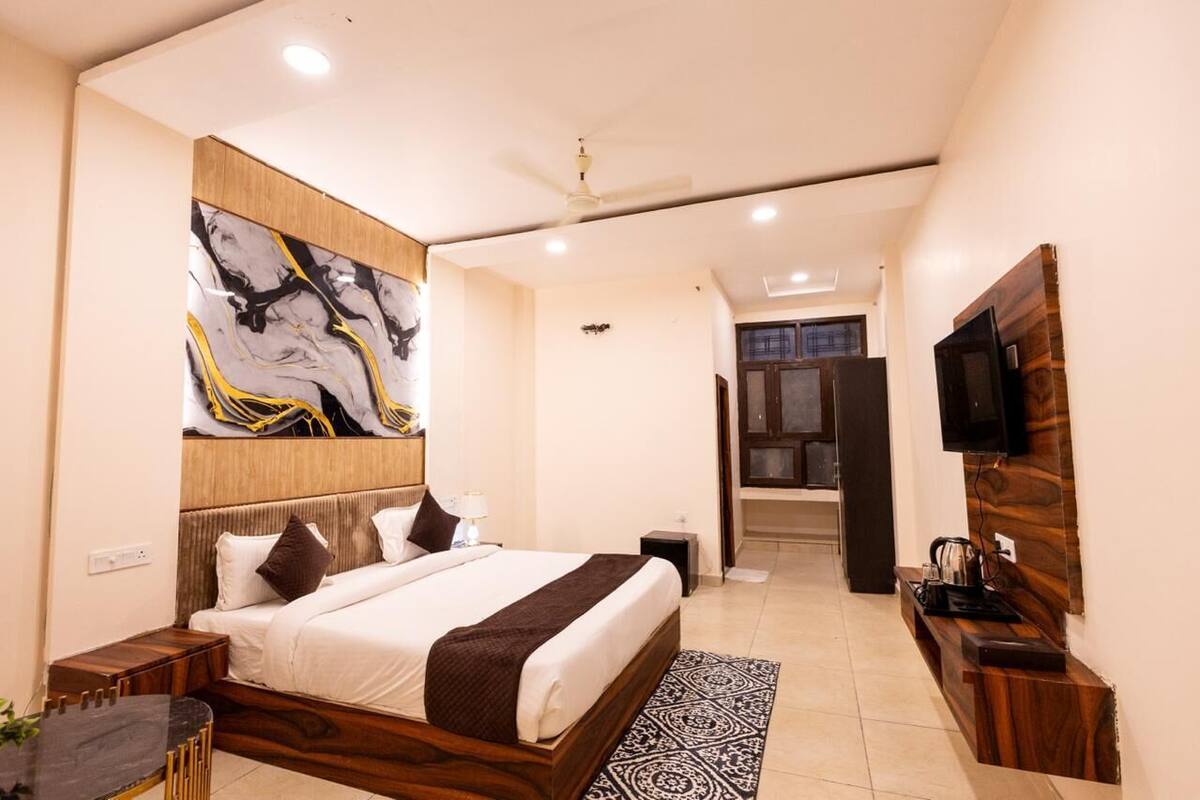 Quarto de hotel moderno com uma cama grande, TV de tela plana e ventoinha no teto.