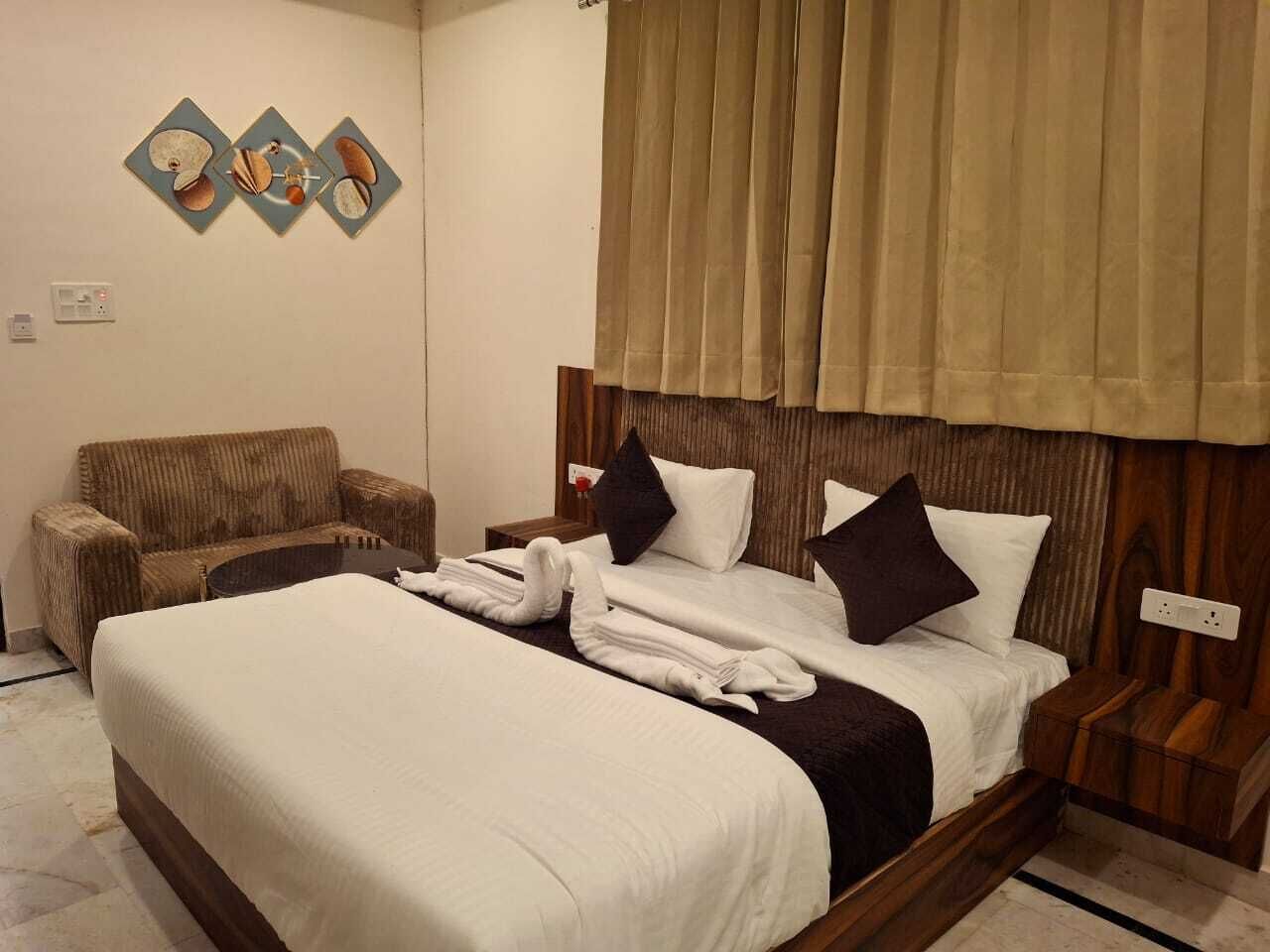 Quarto de hotel com cama, sofá, cabeceira de madeira e obra de arte pendurada na parede.